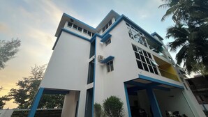 Um edifício moderno com fachada branca e detalhes em azul, apresentando grandes janelas e uma varanda.