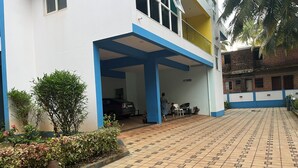 Um edifício com entrada coberta, um pátio com azulejos e um carro estacionado.