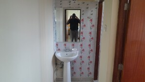 Casa de banho com uma pia branca, um espelho e azulejos com padrão floral.