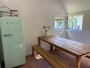 Cozinha com geladeira vintage Smeg, mesa de madeira e um banco.