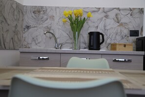 Uma cozinha moderna com painel de fundo de mármore, uma cafeteira preta e um vaso de tulipas amarelas sobre o balcão.