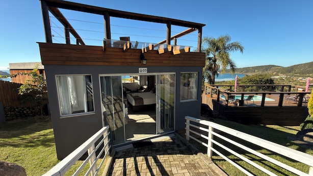 Uma pequena pensão com um único quarto, varanda, piscina e vista para o oceano.