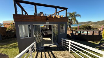 Uma pequena pensão com um único quarto, varanda, piscina e vista para o oceano.