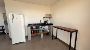 Uma cozinha compacta com geladeira, micro-ondas, cafeteira e uma mesa pequena.