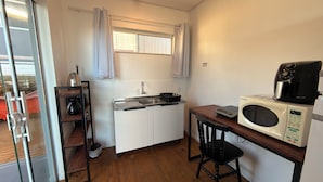 Uma cozinha compacta equipada com micro-ondas, cafeteira e uma pia pequena.