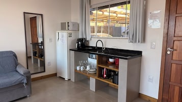 Uma cozinha compacta com geladeira embutida, cafeteira e pia.