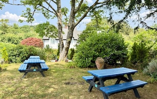 Um jardim com mesas de piquenique e um vaso grande.