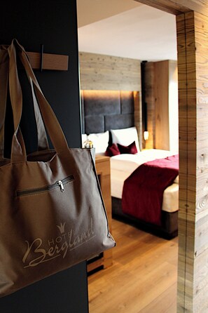 Quarto de hotel com uma cama, uma mesinha de cabeceira e uma sacola pendurada com a inscrição 'HOTEL BERGMUND'.