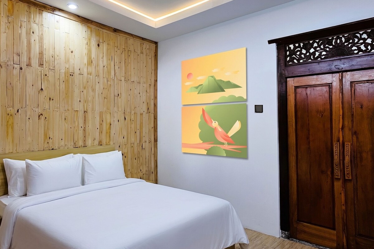 Quarto com painel de parede de madeira, cama com roupa de cama branca, obra de arte pendurada na parede e porta de madeira.