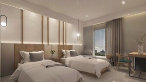 Quarto de hotel moderno com duas camas, uma mesa de trabalho e uma grande janela com vista para a cidade.