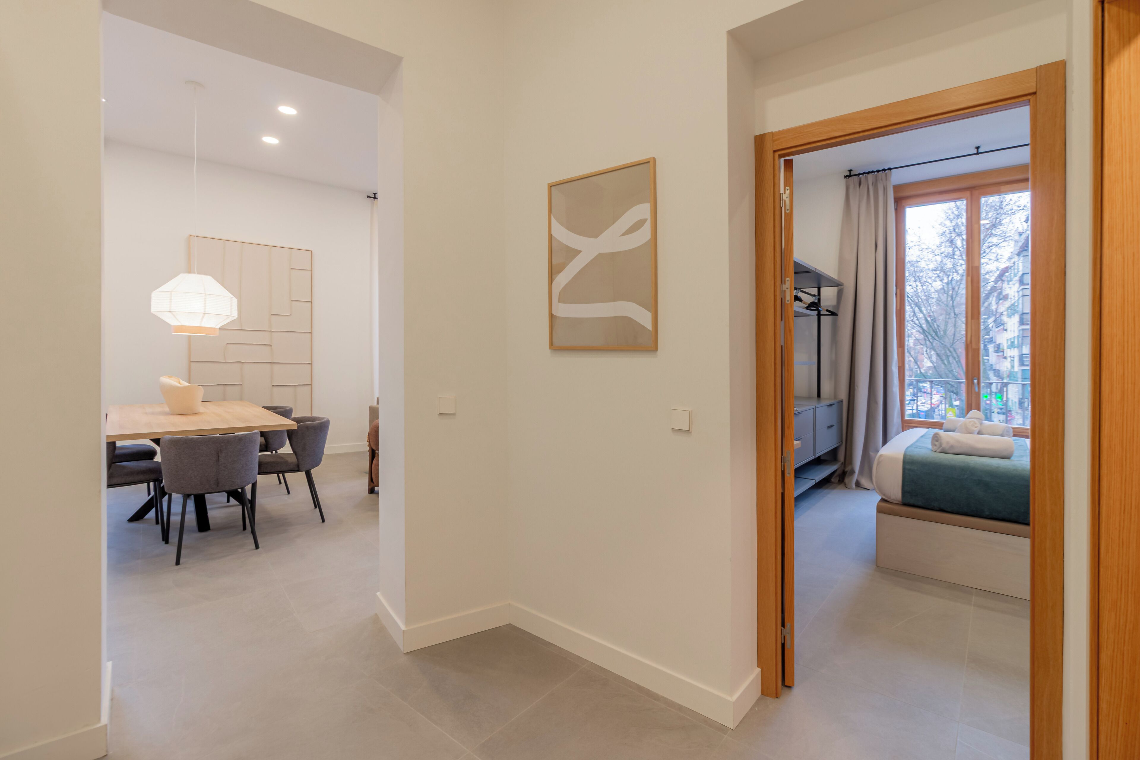 Um interior moderno com área de jantar, um corredor que leva a um quarto e vista para o exterior.