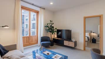 Uma sala de estar moderna com um sofá, uma mesa de centro, uma TV e um vaso de plantas.