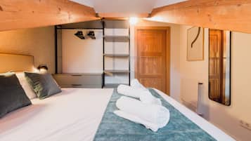 Quarto de hotel com cama, mesa de cabeceira, prateleira na parede, guarda-roupa e espelho.