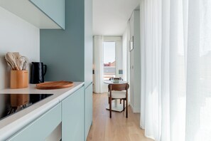 Uma cozinha moderna com tábua de corte de madeira, chaleira preta e suporte de utensílios de madeira.