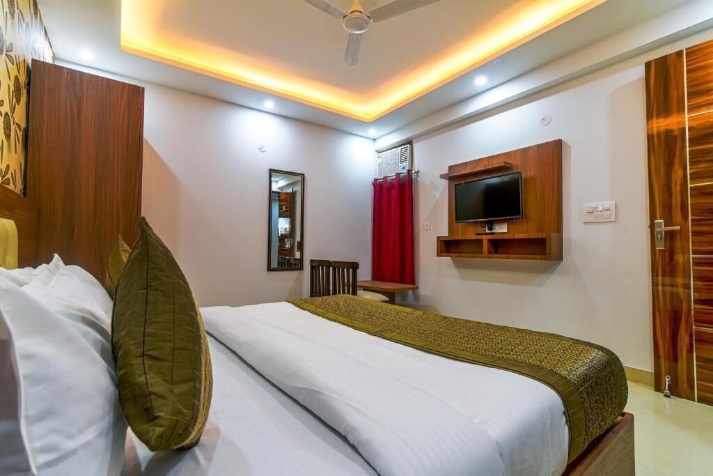 Quarto de hotel com cama, televisão na parede e ventilador de teto.
