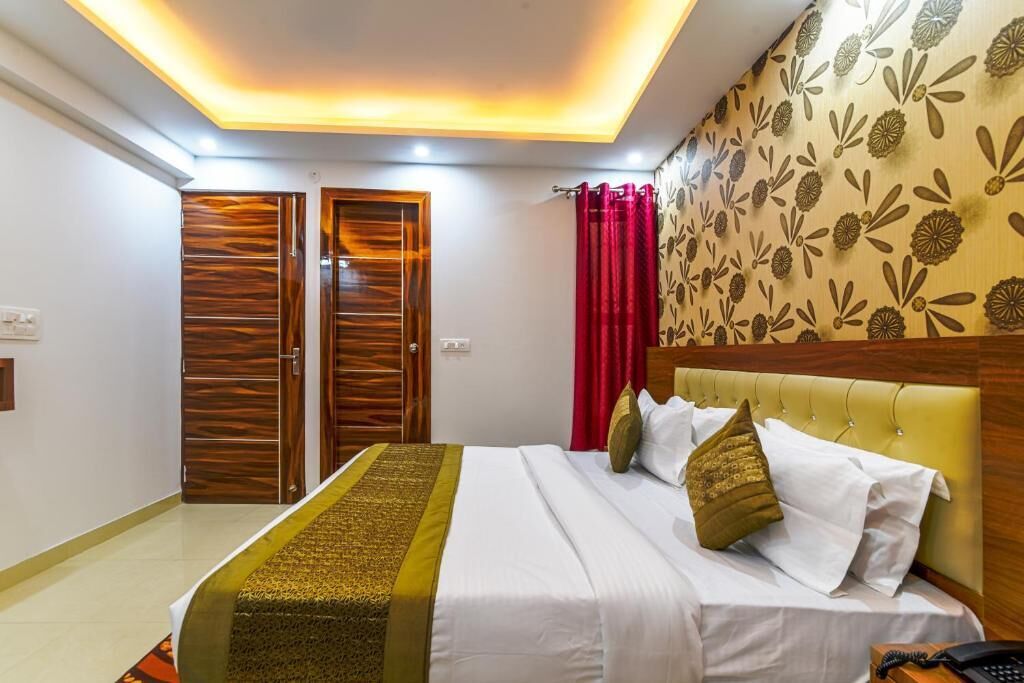 Quarto de hotel com cama, mesa de cabeceira, telefone e porta.