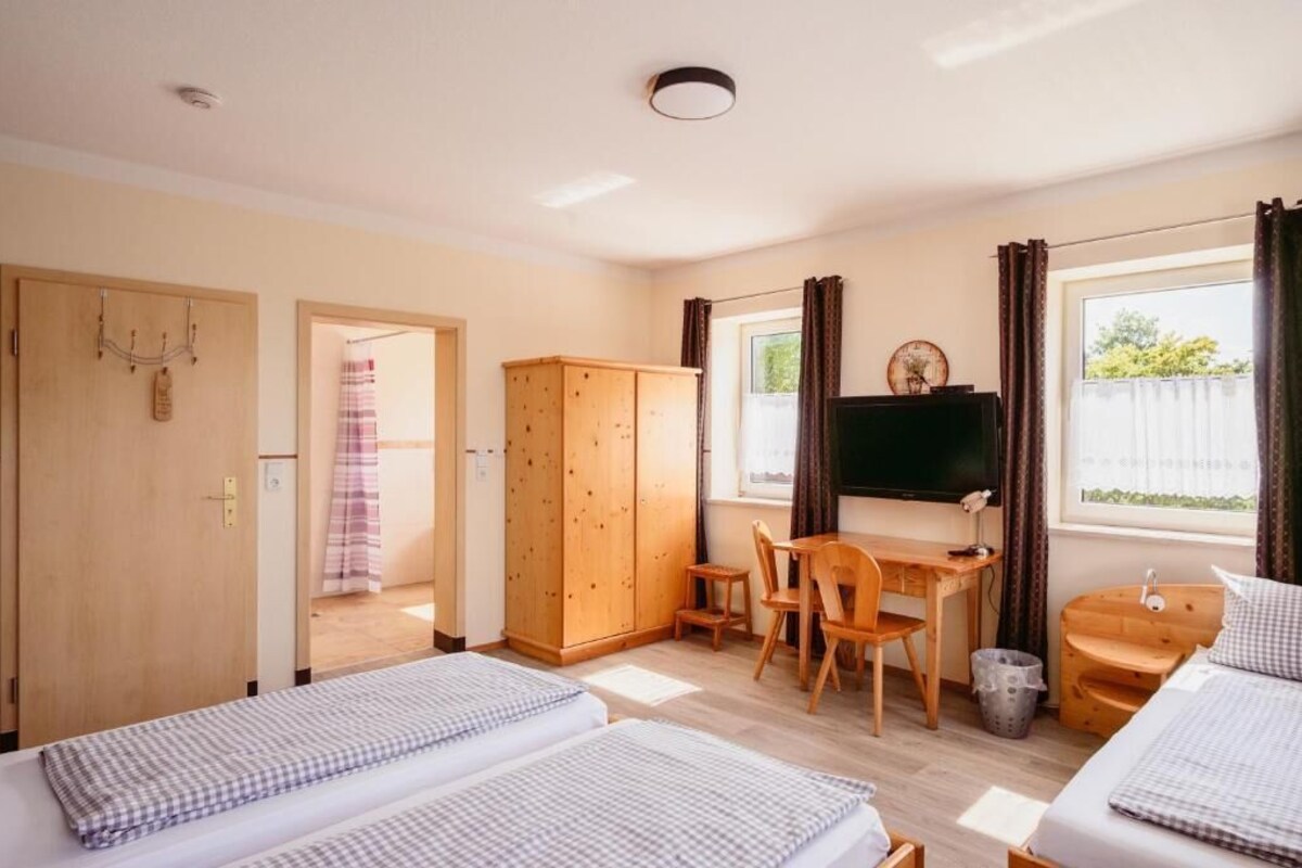 Quarto de hotel com duas camas, uma escrivaninha, uma televisão e uma janela com cortinas.