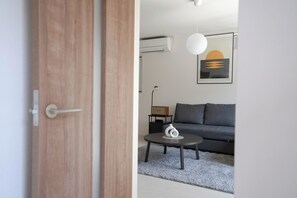 Uma sala de estar moderna com um sofá cinzento, uma mesa de centro redonda e um vaso branco.