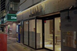 Fachada com uma placa que diz 'LUMA' e um aviso de serviço 24 horas.