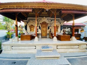 Um templo com altar central, pilares ornamentados e chão de azulejos.