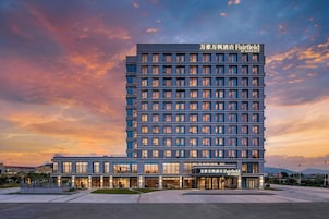 Um hotel com vários andares, fachada moderna, grandes janelas e uma placa indicando ser uma propriedade Marriott.