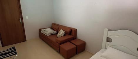 Quarto com cama, sofá, cadeira e porta.
