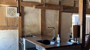 Uma cozinha com vigas de madeira, pia, lava-louças e bancada com dosador de sabão.