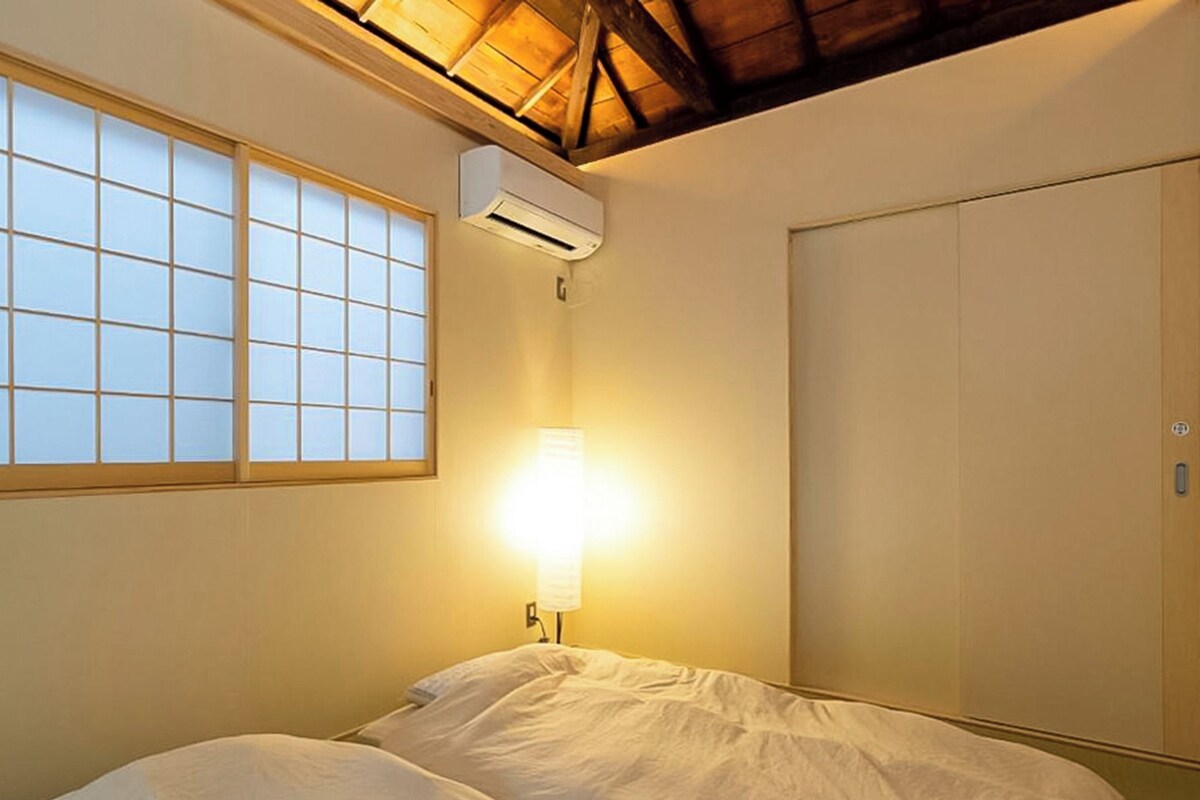 Quarto com cama, janela, ar-condicionado e guarda-roupa.