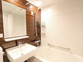 Casa de banho com lavatório branco, espelho, chuveiro e secador de mãos.