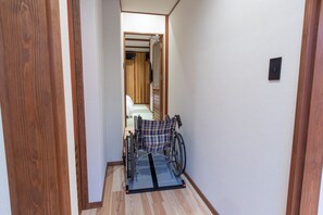 Corredor acessível para cadeiras de rodas, com piso de madeira e uma porta à esquerda.
