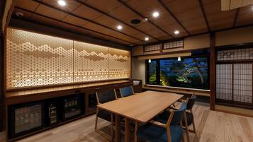 Um quarto japonês tradicional com tatames, uma mesa baixa e vista para a natureza através de uma janela.