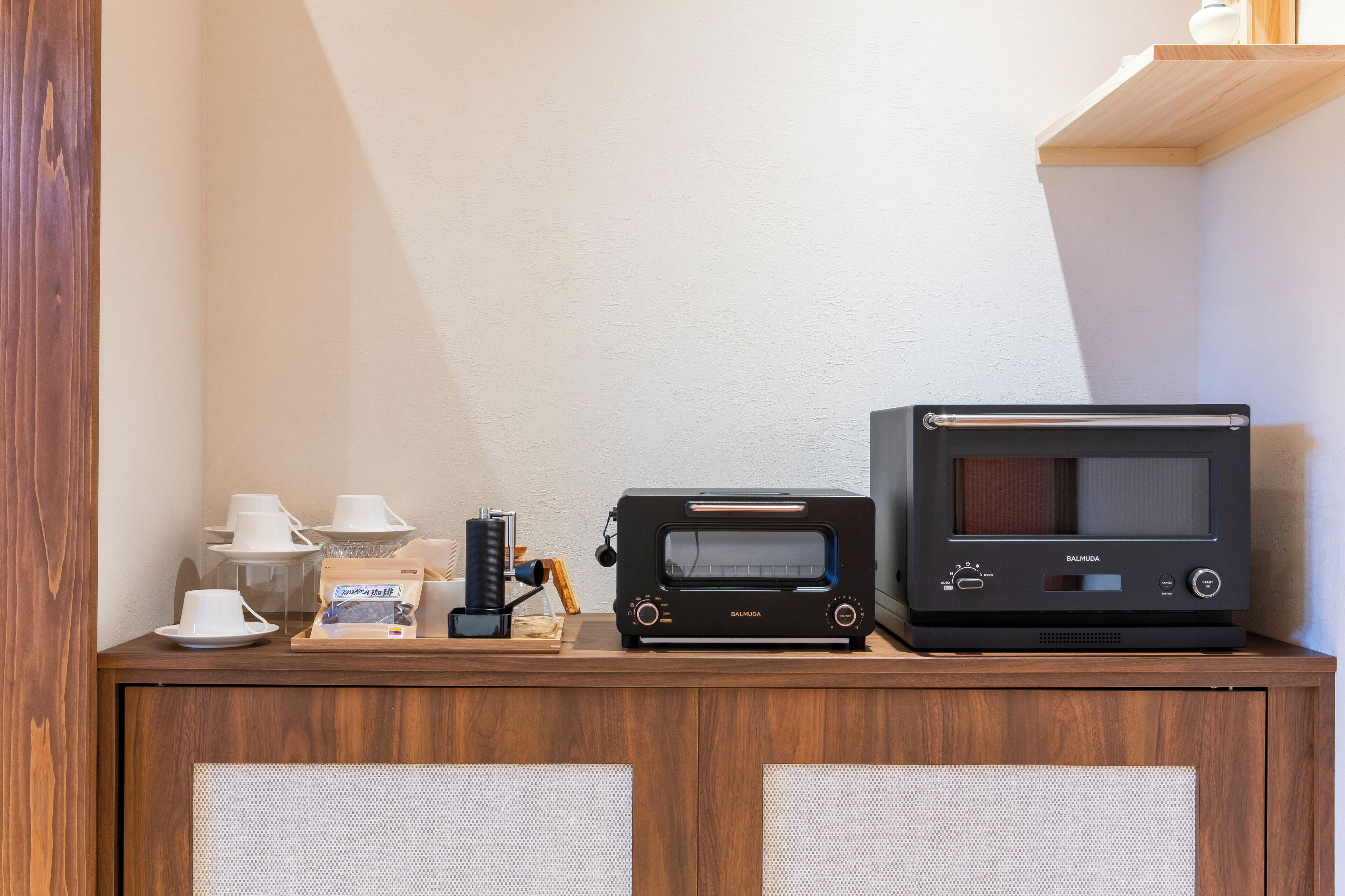 Uma cozinha compacta com micro-ondas, torradeira e cafeteira em bancada de madeira.