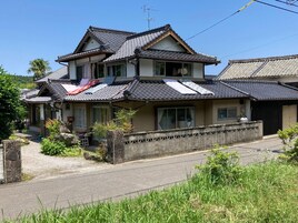 Uma casa japonesa tradicional com telhado de telhas, várias janelas e uma parede de pedra frontal.