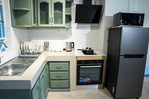 Uma cozinha compacta com forno embutido, micro-ondas e geladeira.