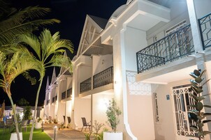 Um hotel com várias andares, varandas, área de estar ao ar livre e palmeiras.