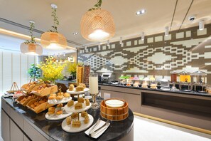 Uma mesa de buffet com diversos alimentos e uma planta decorativa.