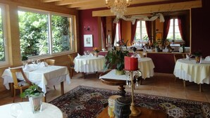 Uma sala de jantar com vigas de madeira, lustres e mesas postas.