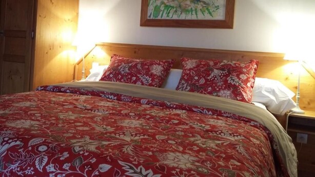Uma cama com roupa de cama florida, uma cabeceira de madeira e um quadro na parede.