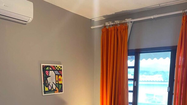 Quarto de hotel com cama, janela com cortinas, um quadro na parede e um aparelho de ar condicionado.