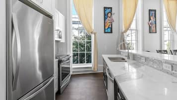 Uma cozinha moderna com geladeira de aço inoxidável, forno, pia e bancada de mármore.