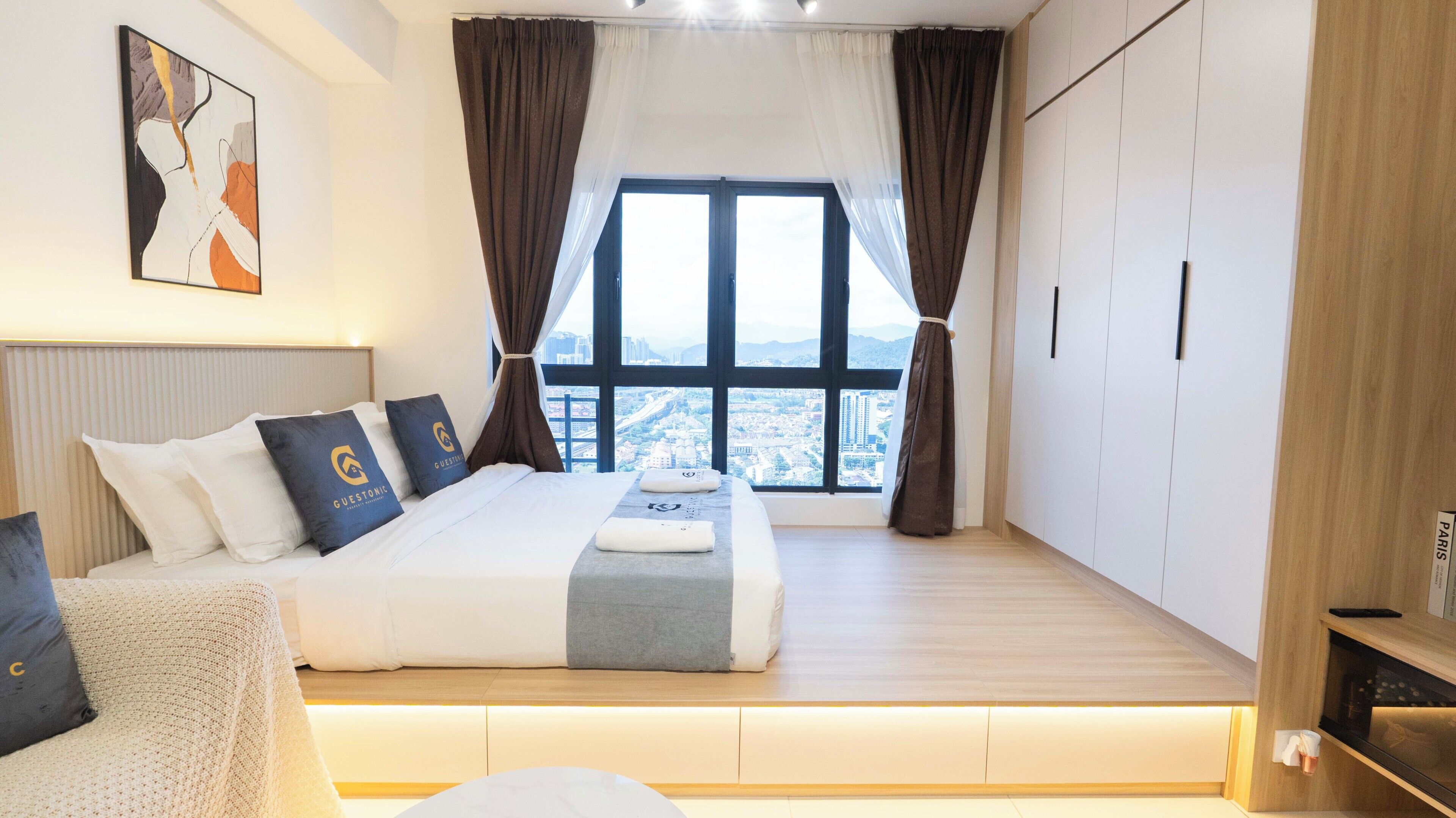 Quarto de hotel moderno com uma cama grande, vista para a cidade e design minimalista.