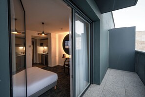 Quarto de hotel compacto com cama, cozinha compacta e pequena área de refeições.