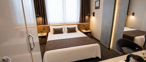 Quarto de hotel com cama grande, escrivaninha, cadeira e espaço para café.