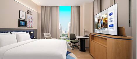Quarto de hotel moderno com uma cama grande, uma escrivaninha, televisão e vista para a cidade.