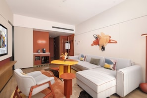 Quarto de hotel moderno com sofá, poltrona e uma pequena mesa redonda com um vaso.