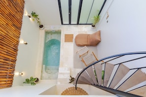 Um interior moderno com escada, um pequeno espaço de estar, um elemento de água e plantas em vasos.