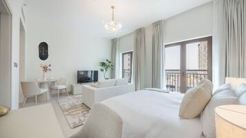 Quarto de hotel com cama, escrivaninha, cadeira, televisão e varanda com vista.
