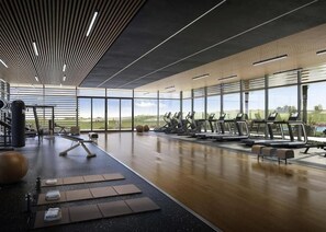 Uma academia com equipamentos de exercício, janelas amplas e piso de madeira.