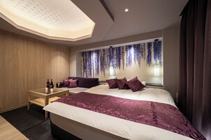 Quarto de hotel moderno com uma cama grande, uma mesinha com bebidas e uma parede decorativa.