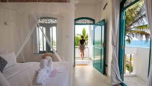 Quarto com cama, dossel e vista para a praia.